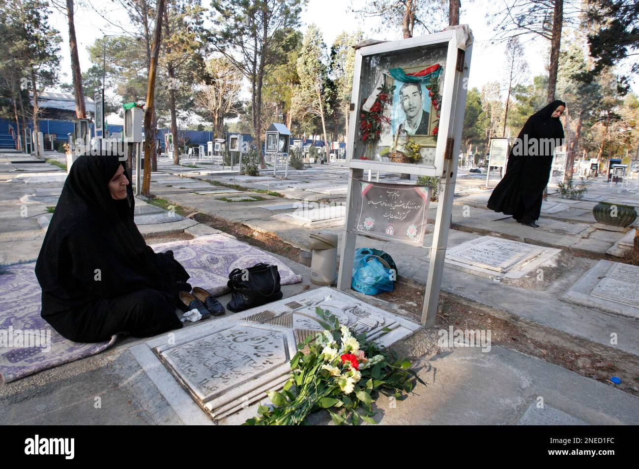 Masoumeh Khoda Gholipour, left, mourns at the grave of her brother ...
