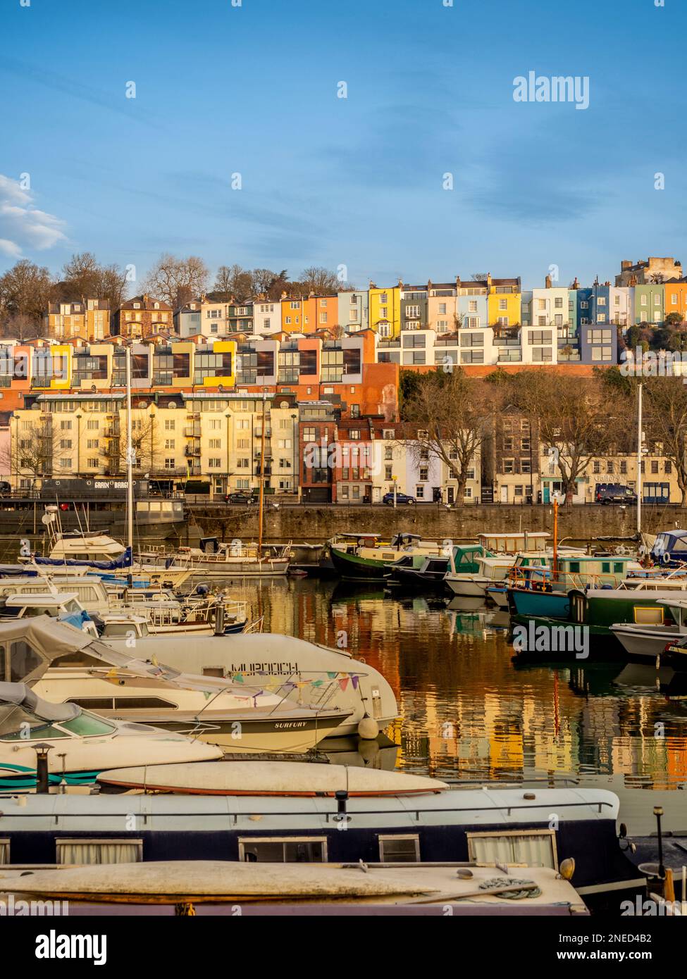 Moored boats in Bristol Marina with colourful painted houses and ...