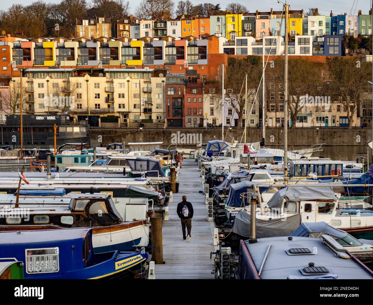 Rear view of man walking down the frost covered wooden jetty of Bristol ...