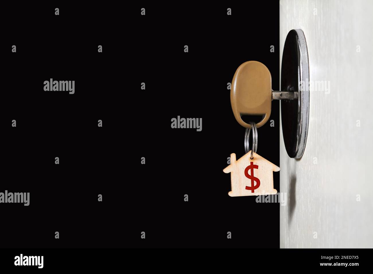 Key with a trinket in the form of a house in the door lock of an open ...