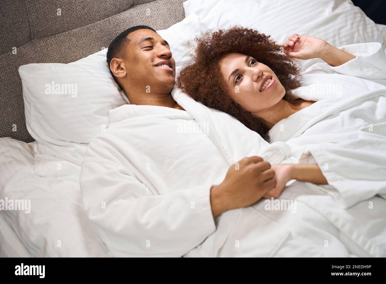 Beautiful multiracial couple lies on the bed in hotel room Stock Photo ...