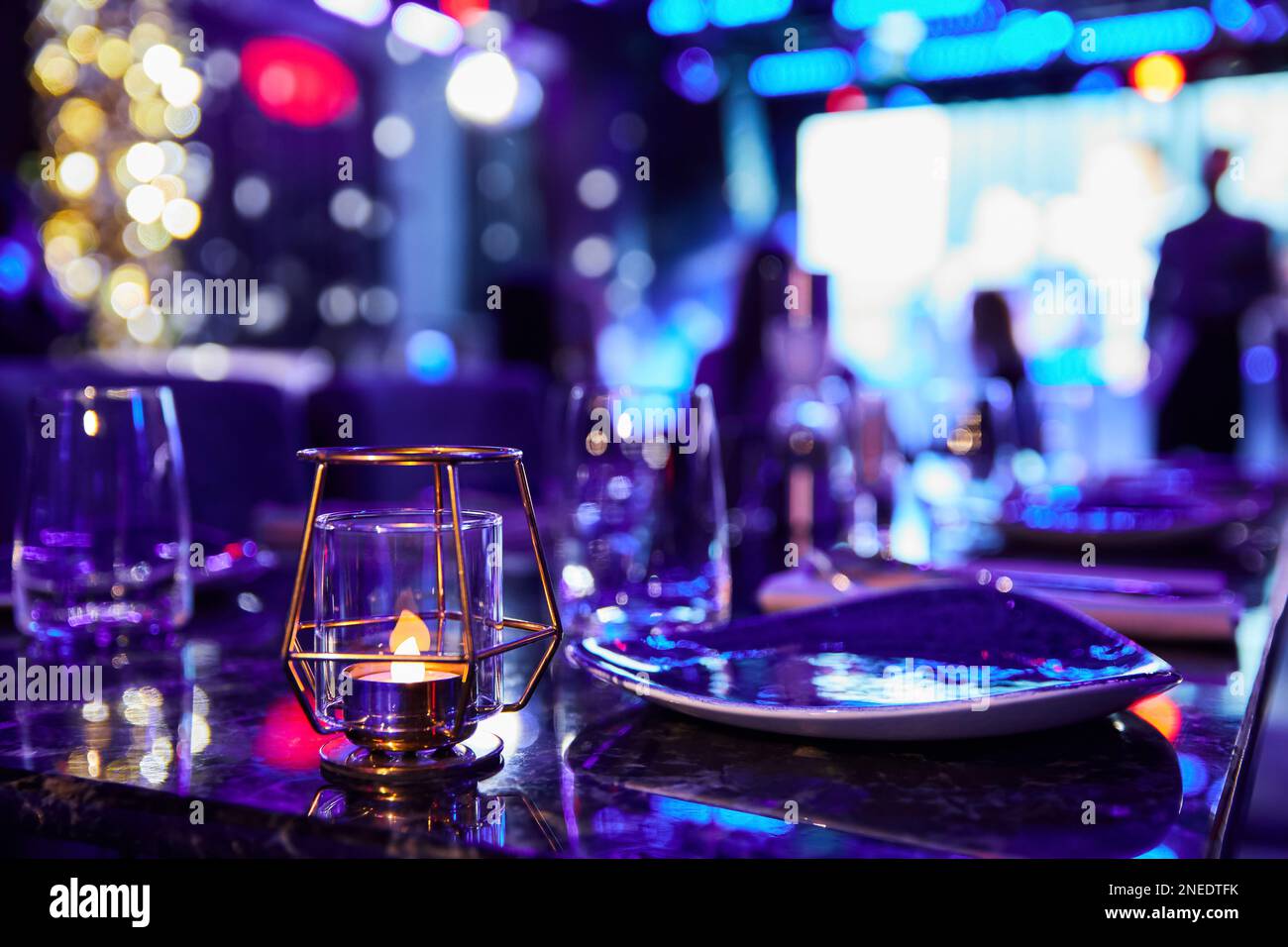 Served table of a night club against the background of multi-colored ...