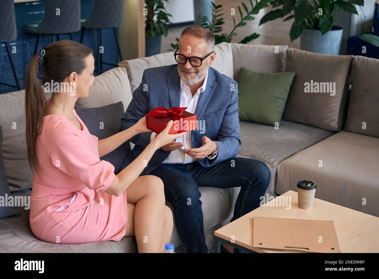 Man in casual clothes accepts gift box from woman's colleague Stock ...