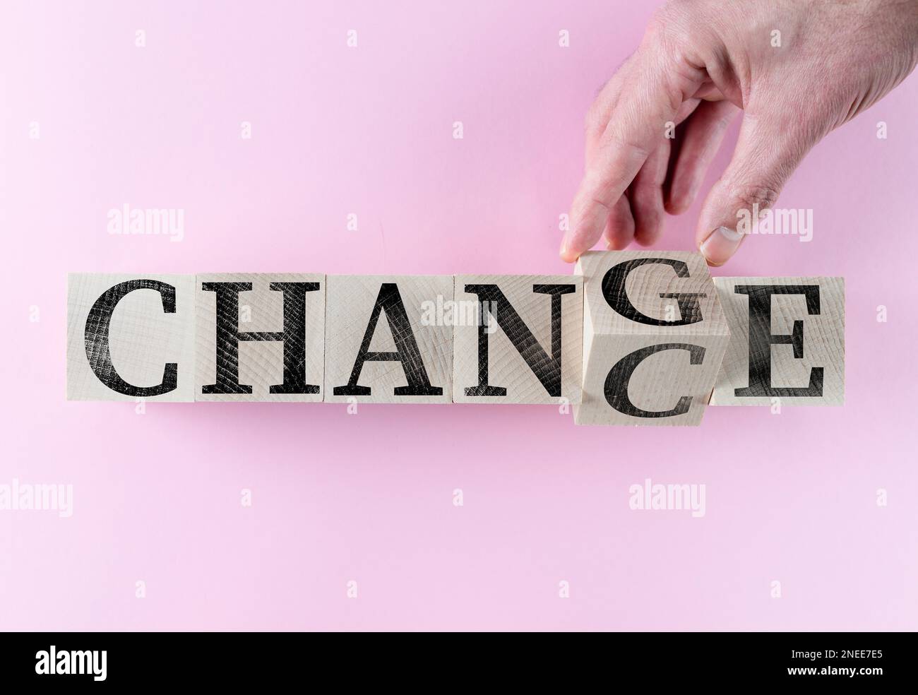 hand turning word CHANGE into CHANCE on wooden blocks against pink ...