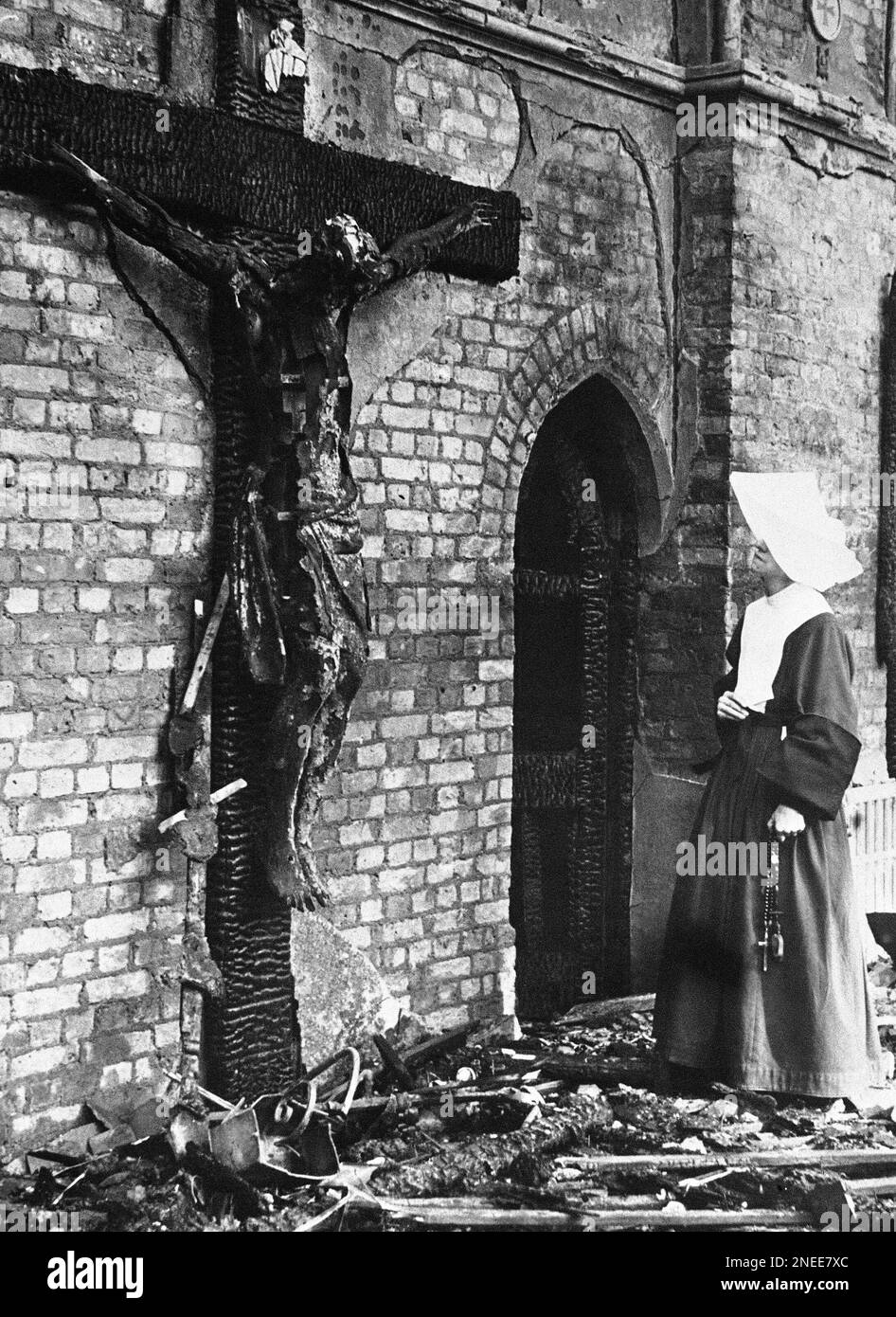 A nun inspects the Crucifix which was almost destroyed by fire but ...