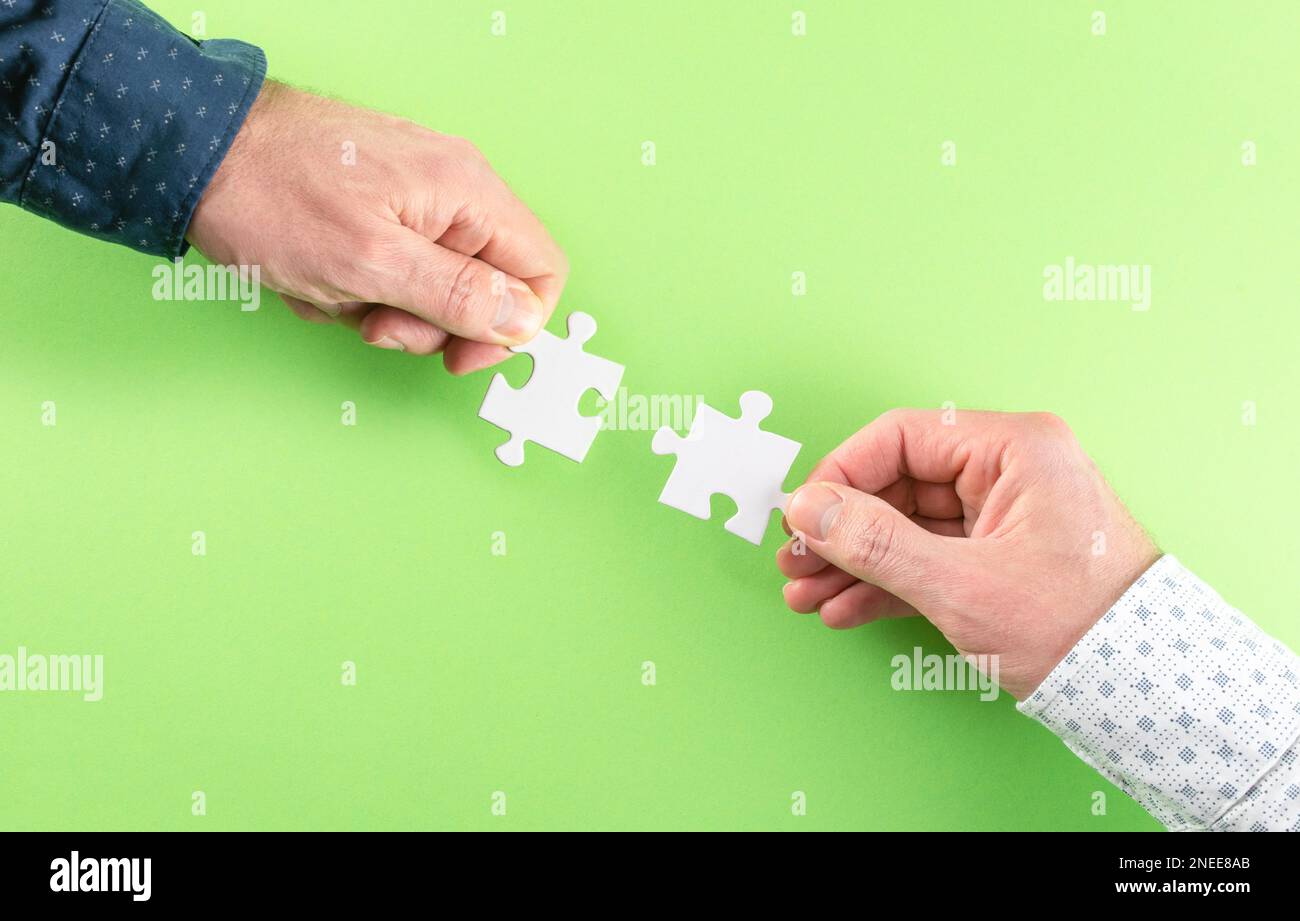hands of two businessmen connecting matching jigsaw puzzle pieces ...