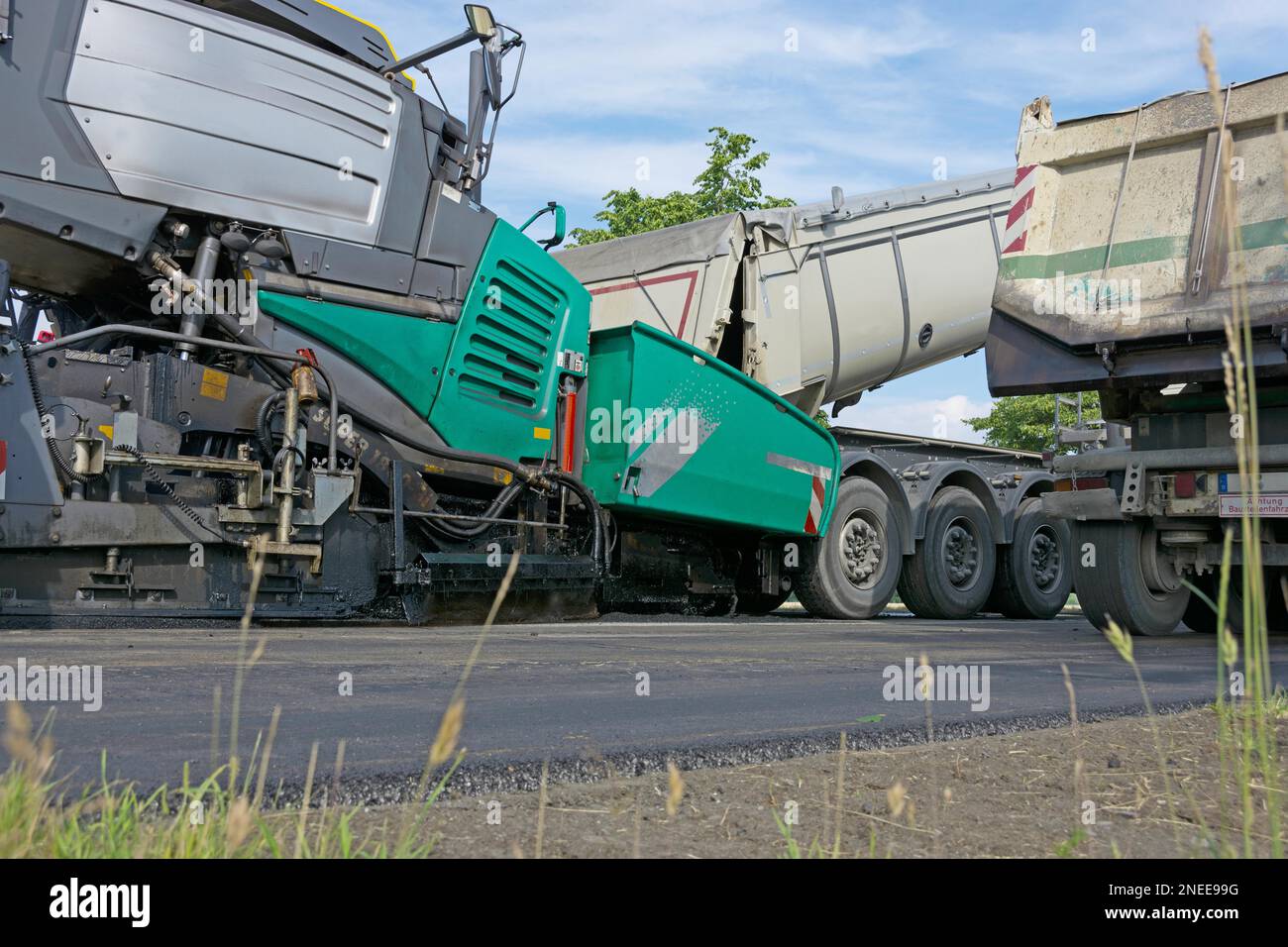 A modern road paver builds in asphalt and is loaded by truck Stock ...
