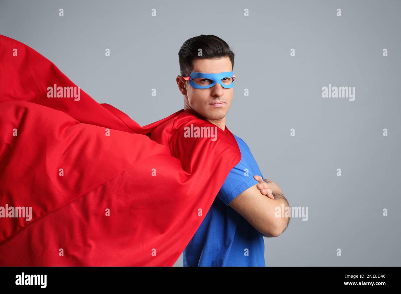 Man wearing superhero cape and mask on grey background Stock Photo - Alamy