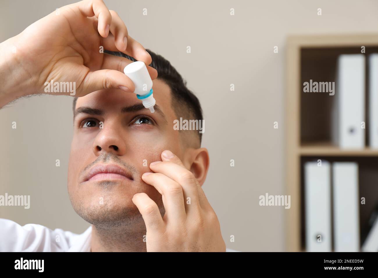 Man using eye drops in light office Stock Photo - Alamy
