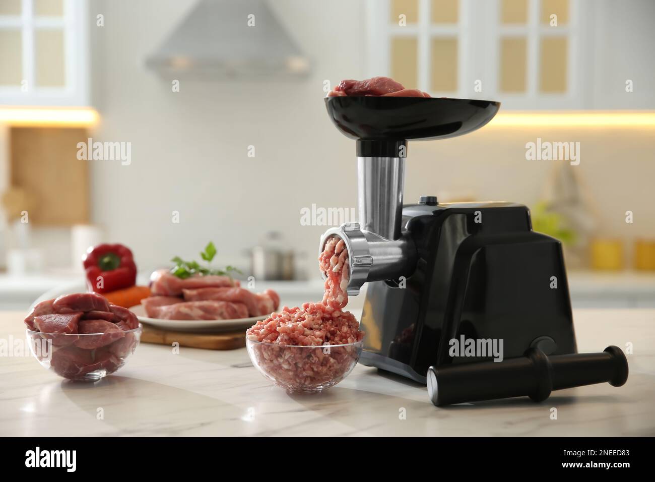 Modern meat grinder and products on white marble table in kitchen ...