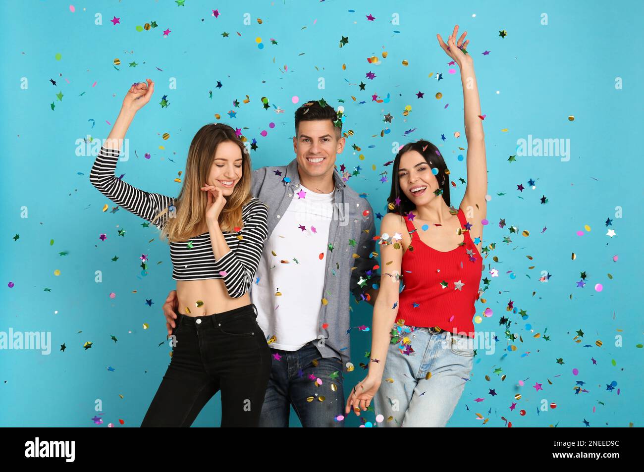 Happy friends and falling confetti on light blue background Stock Photo ...