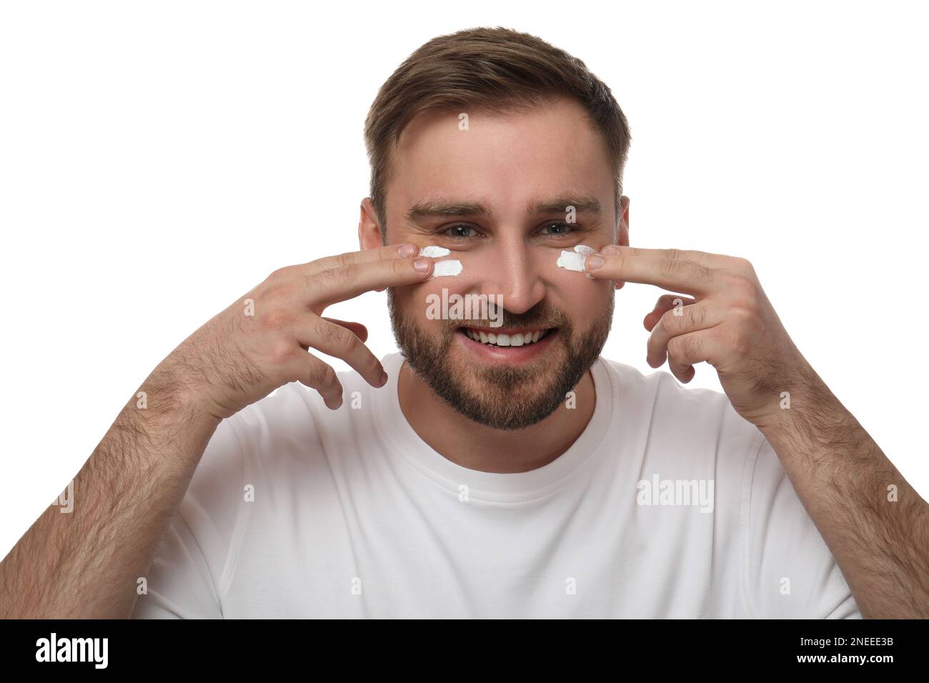 Happy young man applying facial cream on white background Stock Photo ...