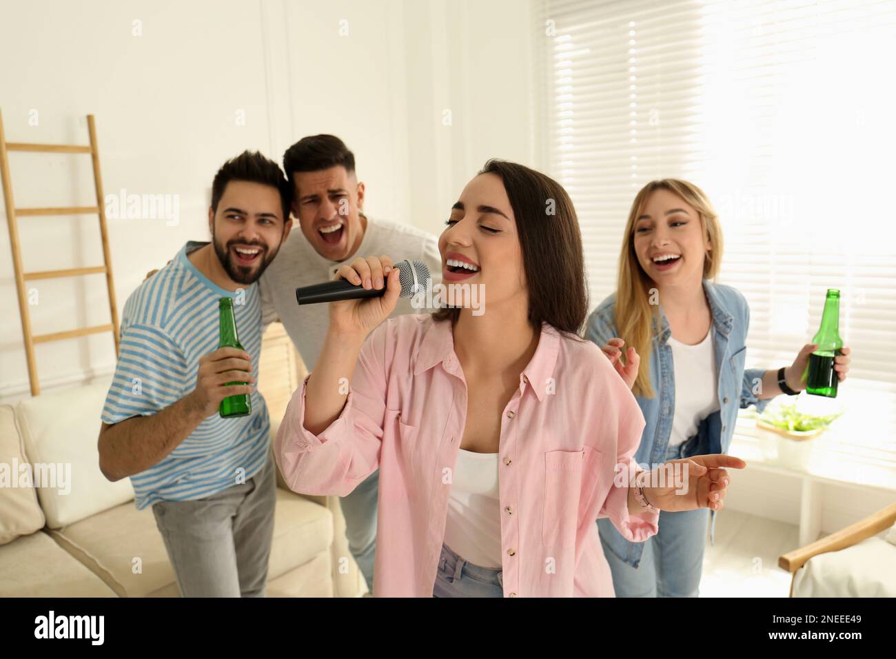Young woman singing karaoke with friends at home Stock Photo - Alamy