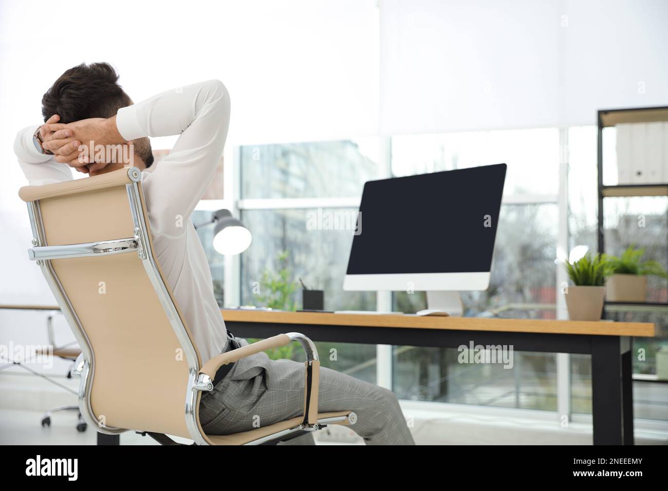 Young businessman relaxing in office chair at workplace, back view ...