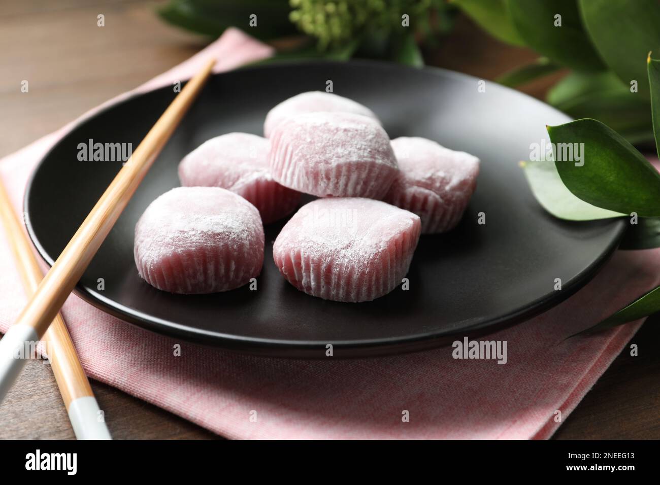Black plate with delicious mochi and chopsticks on wooden table ...