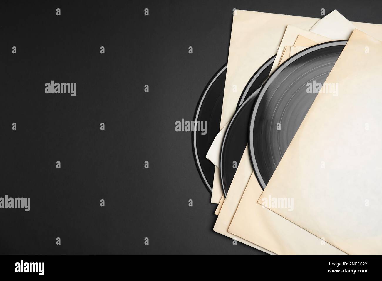 Vintage vinyl records in paper sleeves on black background, flat lay ...