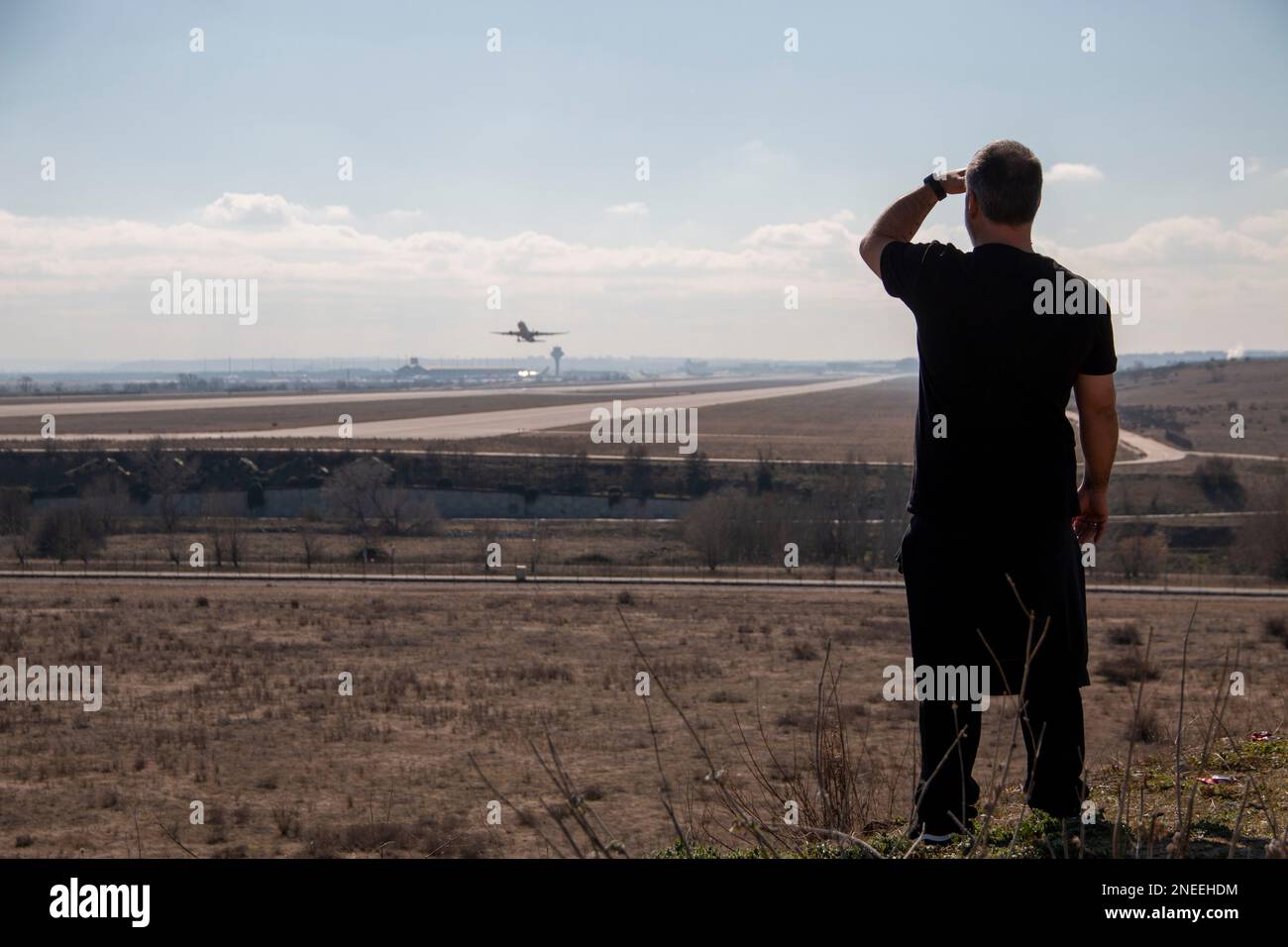 Slightly bald adult man dressed in black watching and pointing as ...
