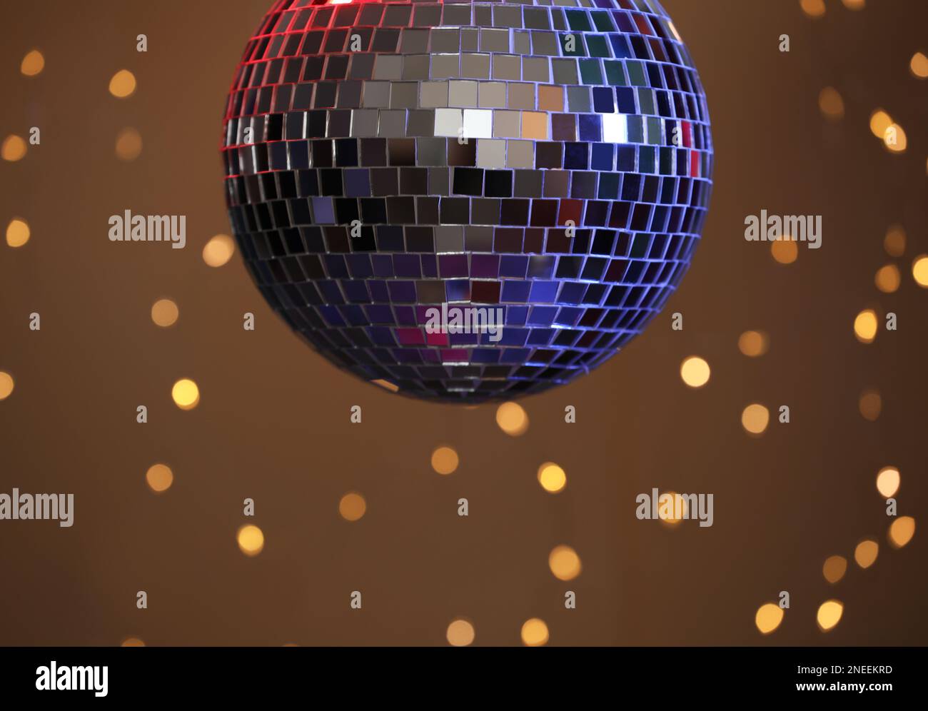 Shiny disco ball against blurred lights on brown background, closeup ...