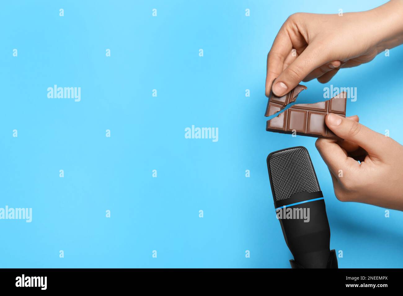 Woman making ASMR sounds with microphone and chocolate on light blue ...