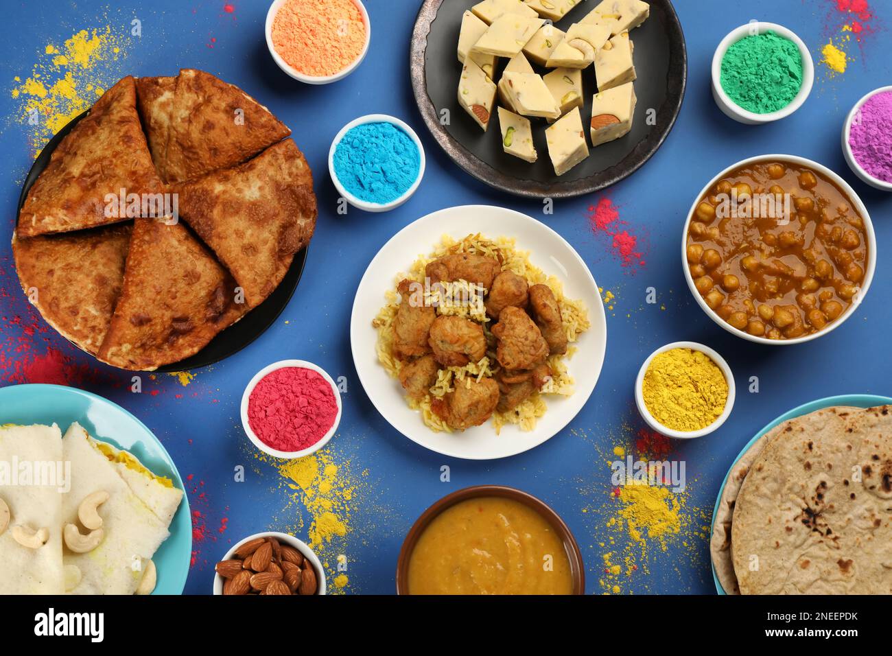 Traditional Indian food and color powders on blue background, flat lay ...