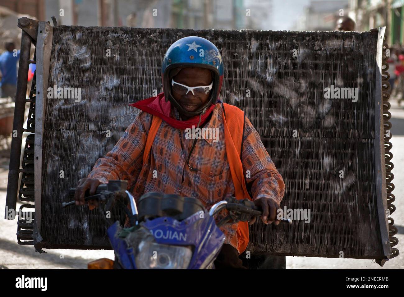 A man carries an air conditioning unit on the back of his motorcycle ...