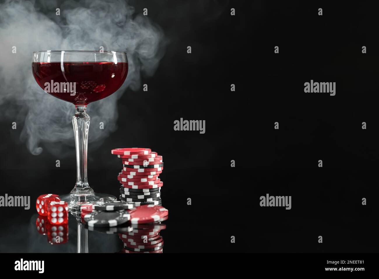 Casino chips, dice and glass of wine on dark background with smoke ...