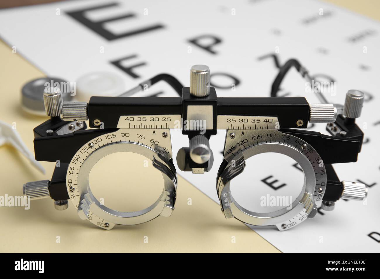 Trial frame with eye chart test on beige background, closeup ...