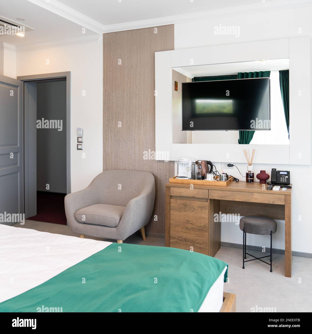 A modern interior of a hotel room with wooden writing table, TV and a ...