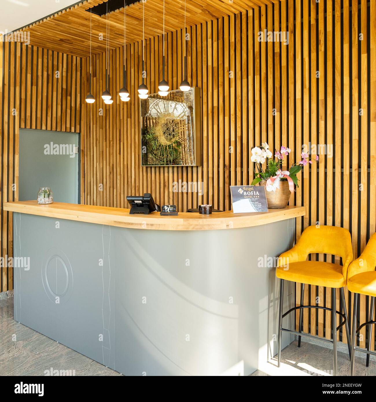 A closeup of a reception desk standing in front of a wooden slats wall ...