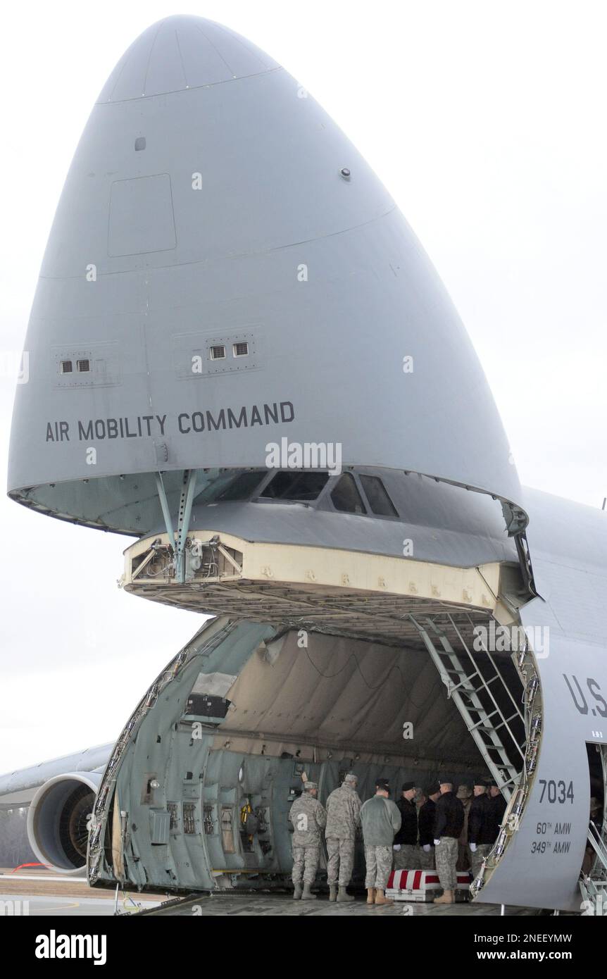 An Army carry team waits to lift a transfer case containing the remains ...