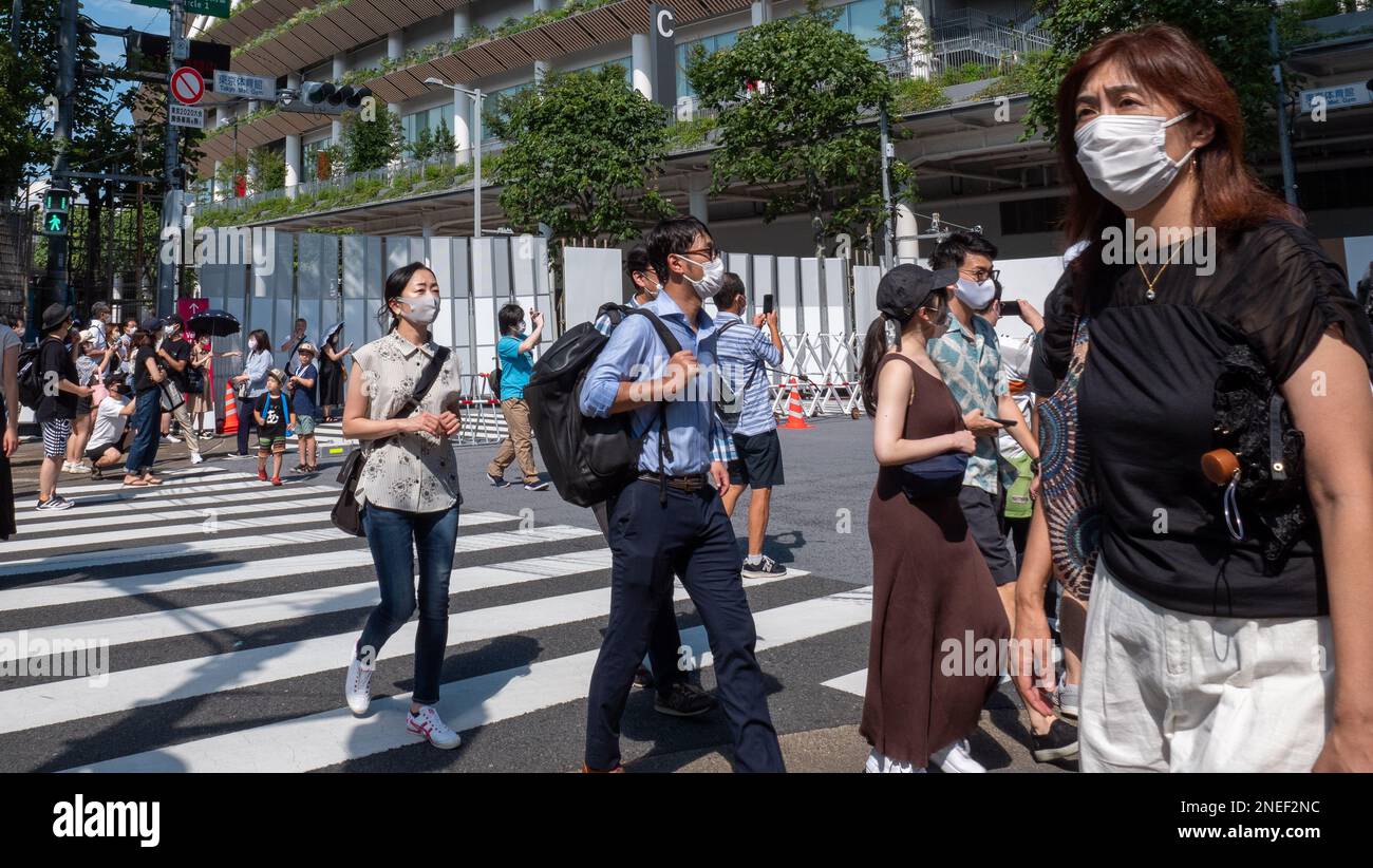 A crowd of people walk on a zebra crossing past the Olympic Stadium in ...