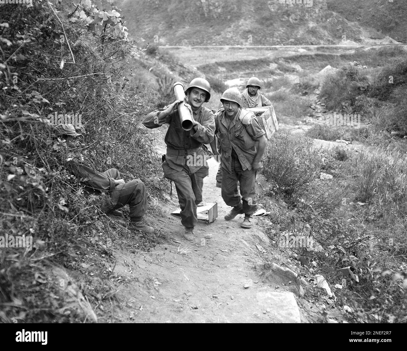 Smiling Frenchmen lug equipment up a trail toward Heartbreak Ridge on ...