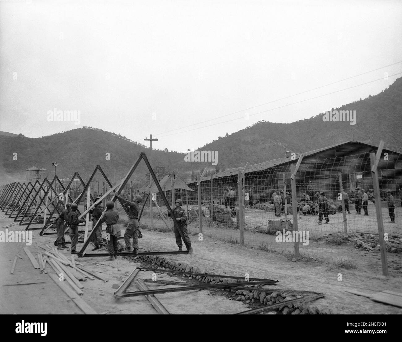 American soldiers erect large metal beams around a communist prisoner ...