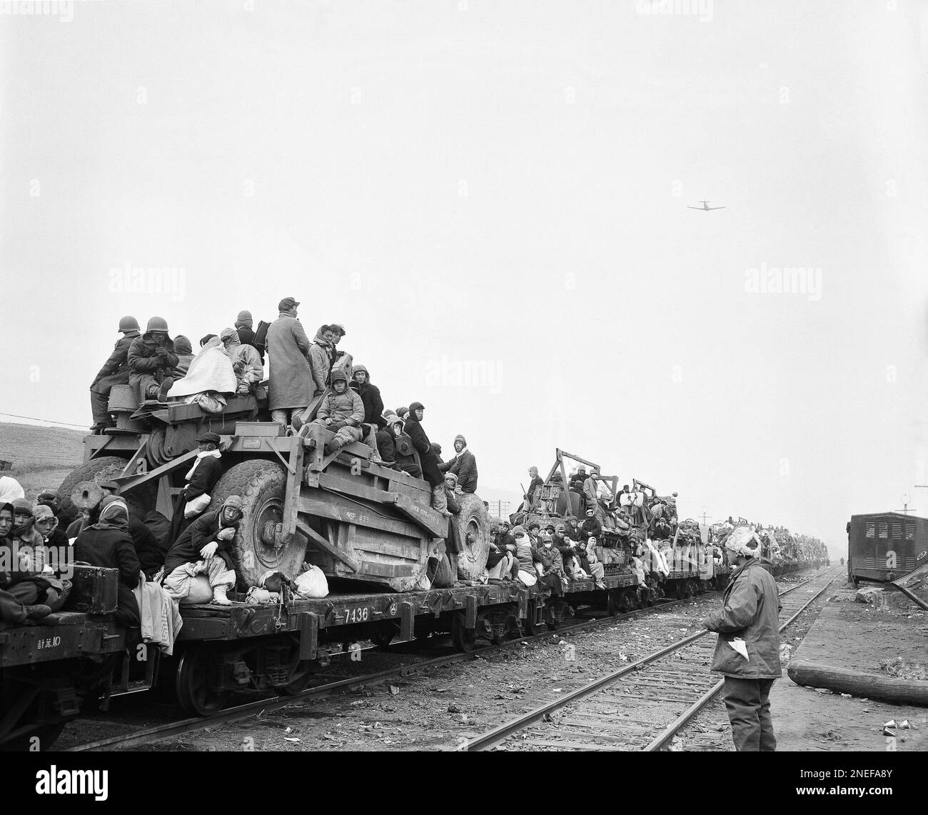 Refugees and soldiers, and salvaged heavy equipment loaded on trains ...
