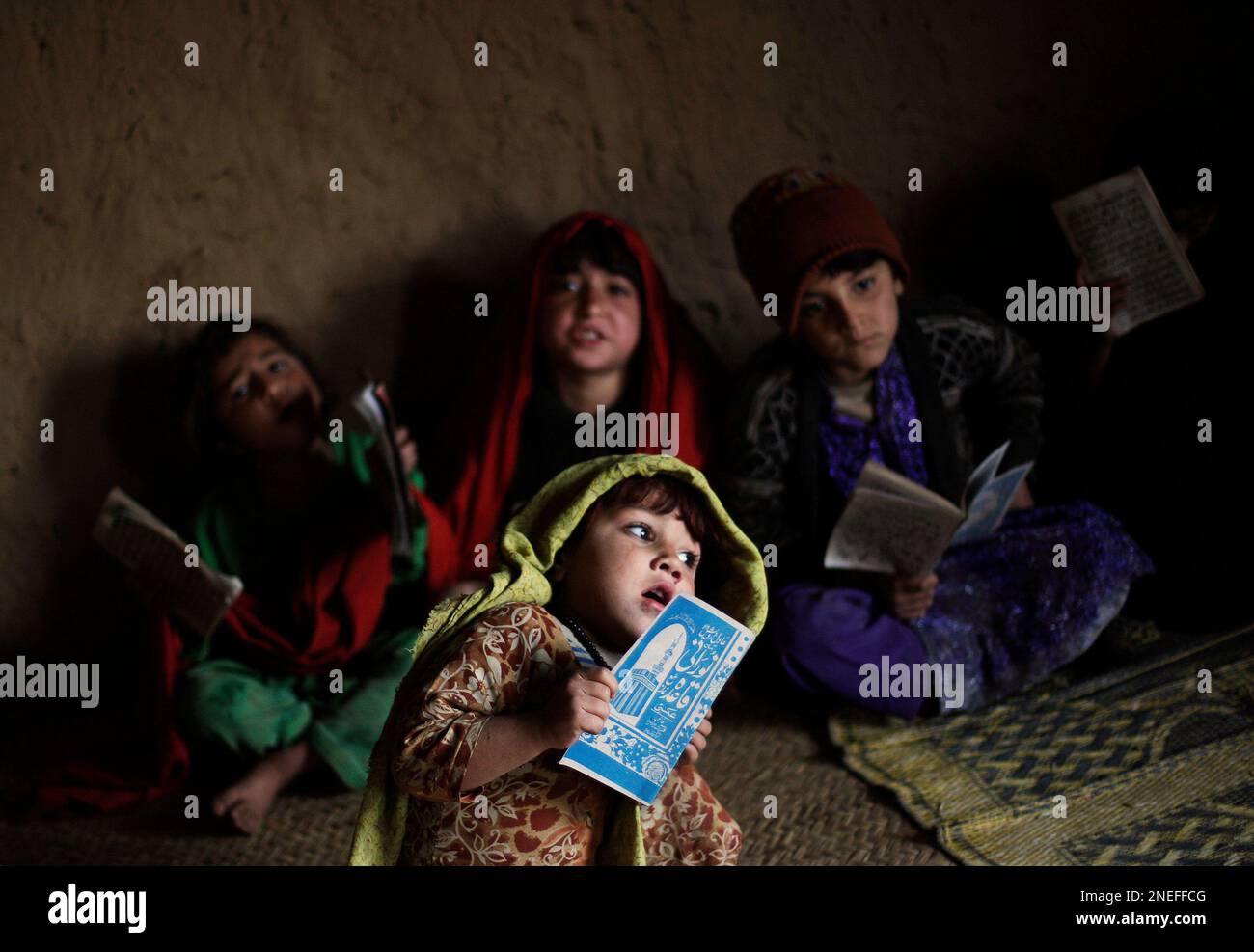 Afghan refugee girls repeat verses of the Quran after an Imam, during ...