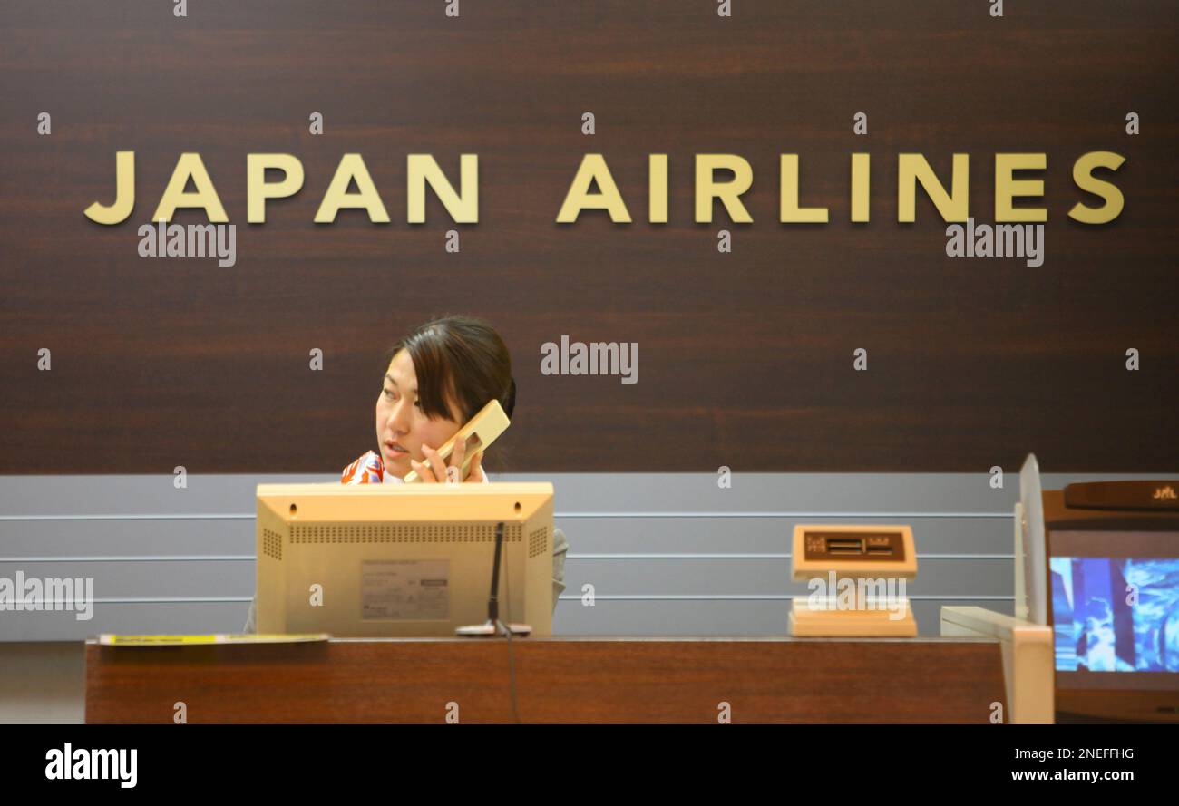 Japan Airlines' first class check in counter staff talks on phone at ...