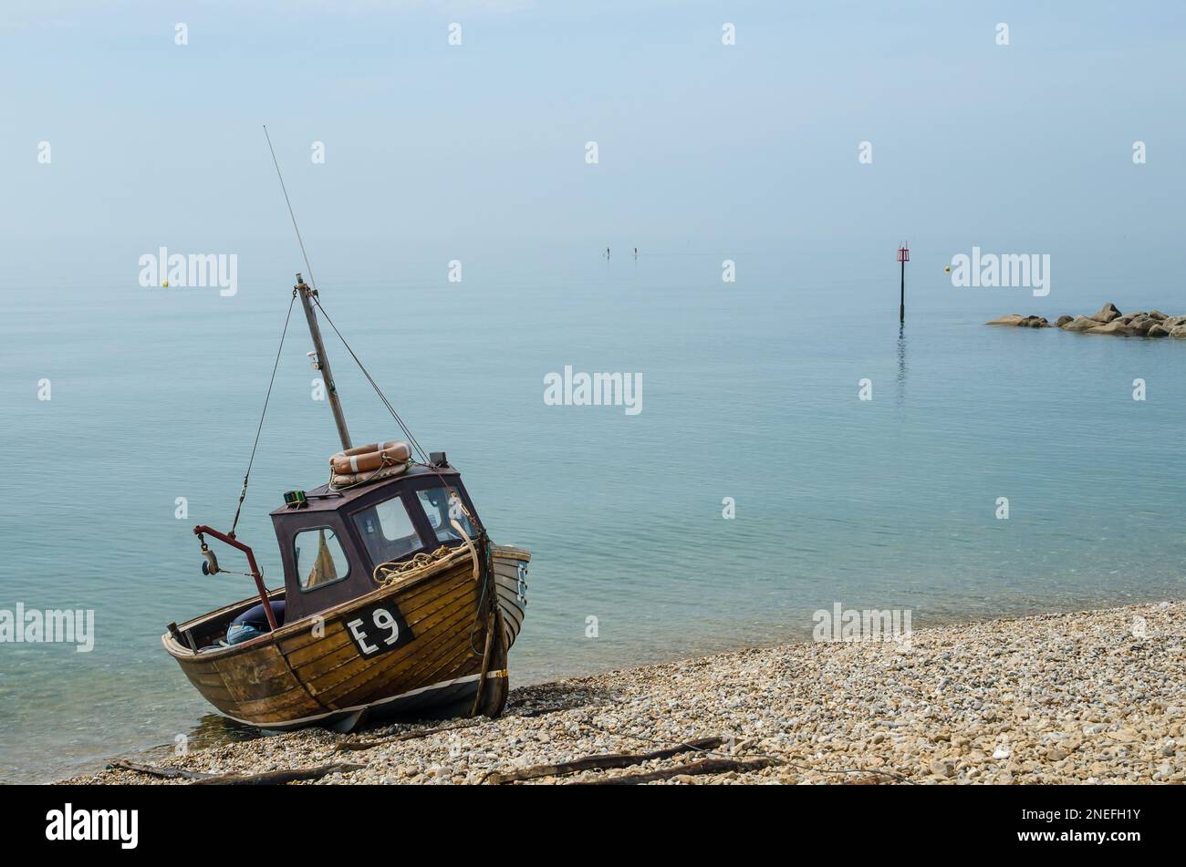 A traditional old wooden hulled fishing boat on the shingle beach at ...