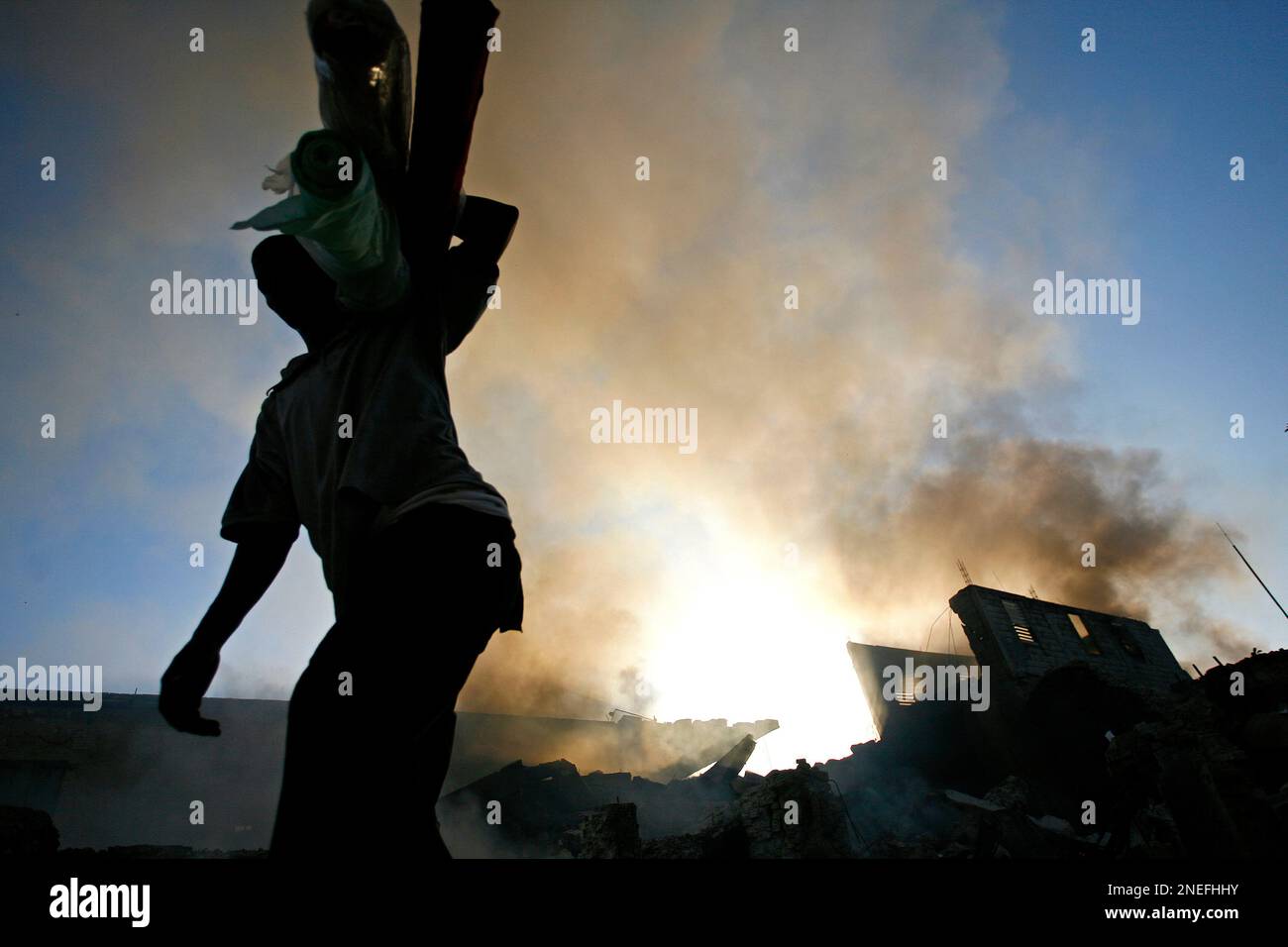 A man carries goods taken from a store damaged during last week's ...