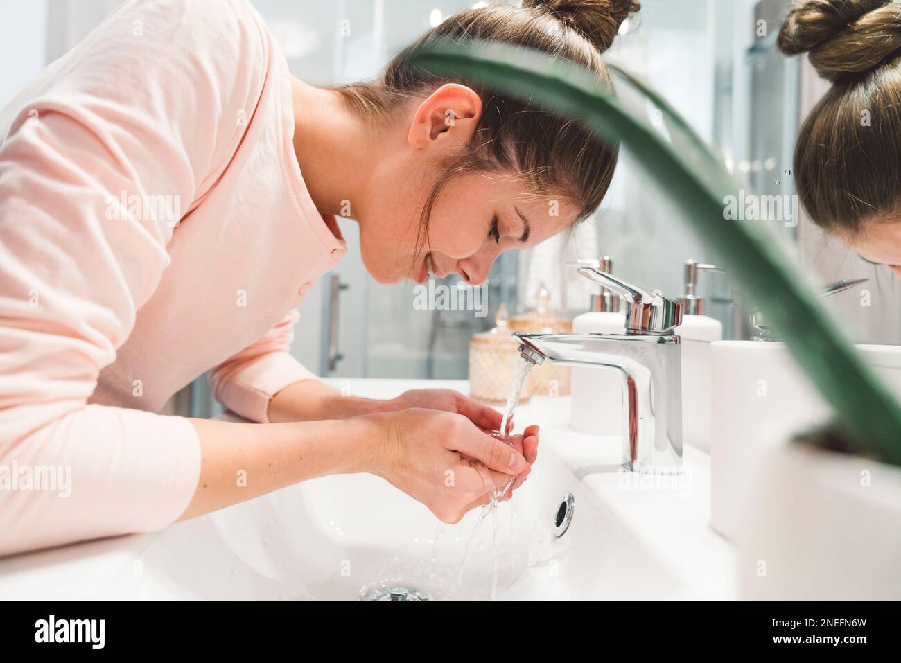 Side view of a woman washing her face in the sink in the morning when ...