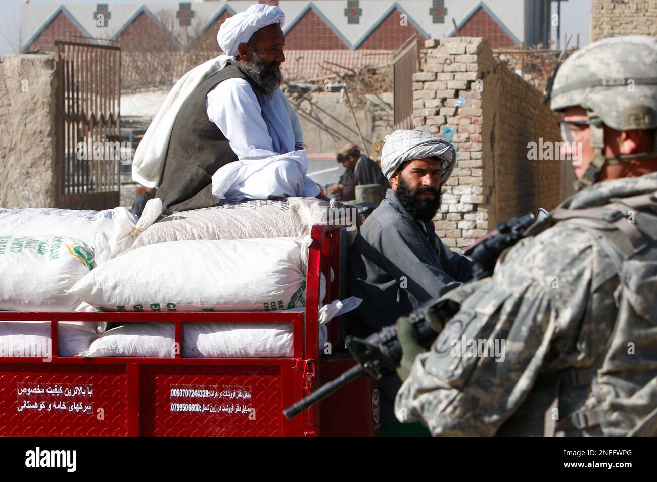 Afghan men drive past Cpl. Jeremy Newman from Little Rock, Ark., of the ...