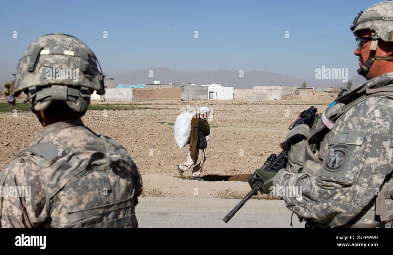 An Afghan man walks past soldiers of the 293rd Military Police Company ...