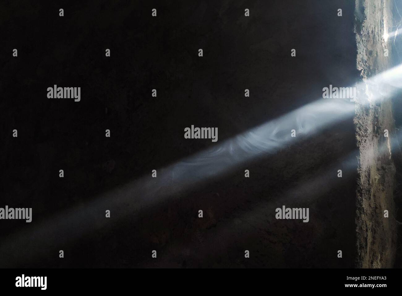 A ray of light passing through a smoky room by a broken shutter of an ...