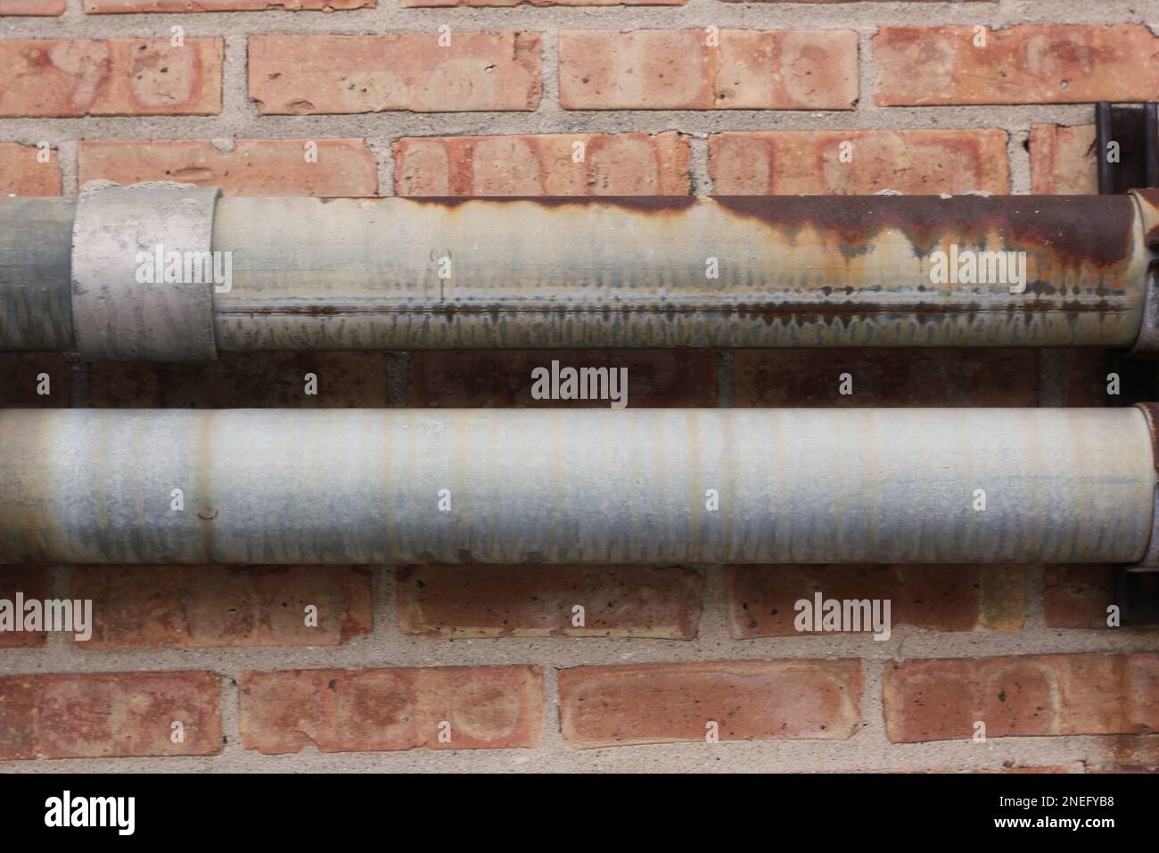 Typical common metal pipes running along a brick wall Stock Photo - Alamy