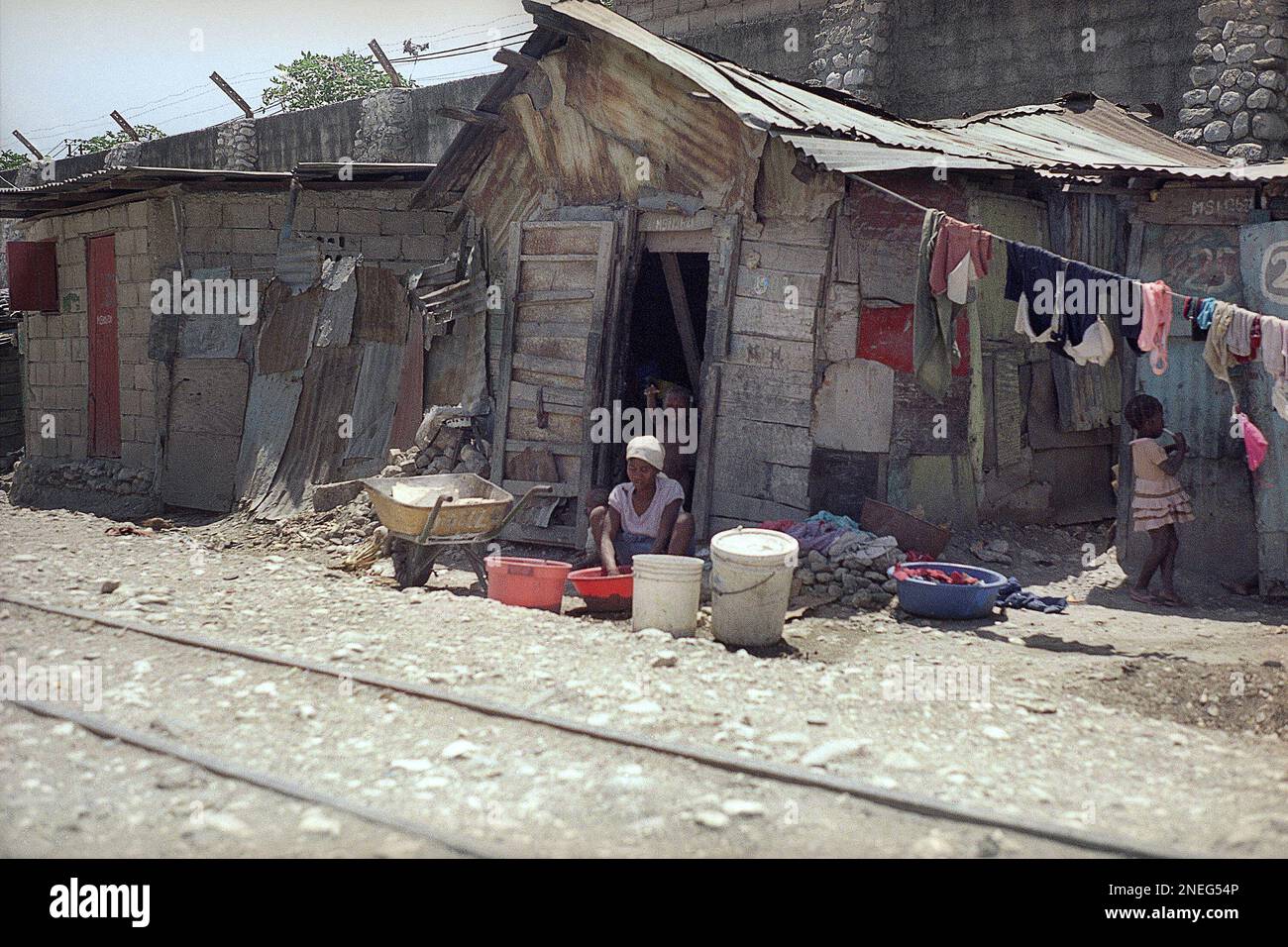 A woman squats by the doorway of her home in the slum of Cite Soleil ...
