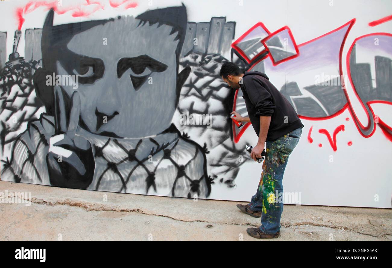 A graffiti artist puts the finishing touches to a piece of work ...