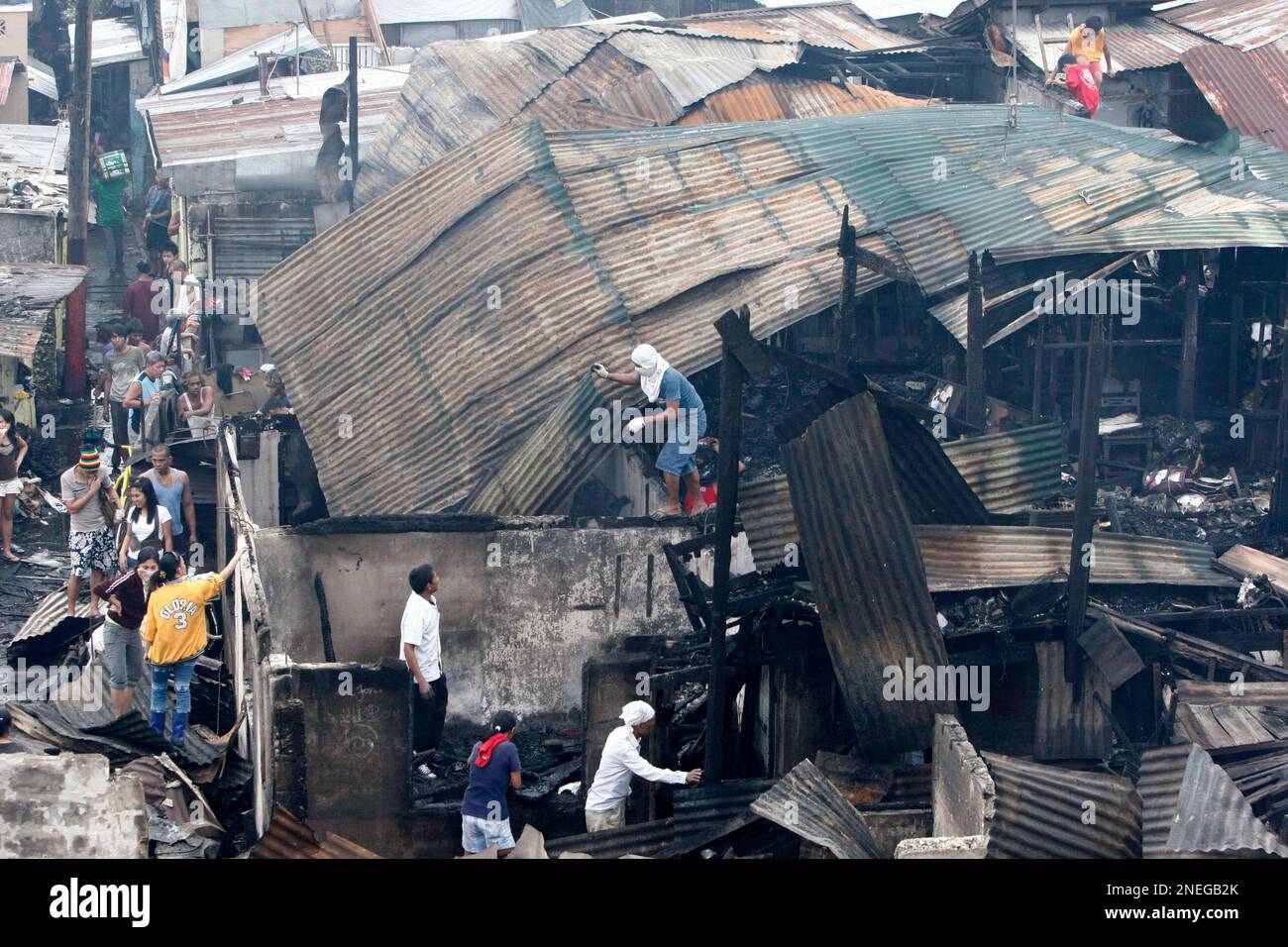 Residents sift through debris a day after a fire razed close to a ...