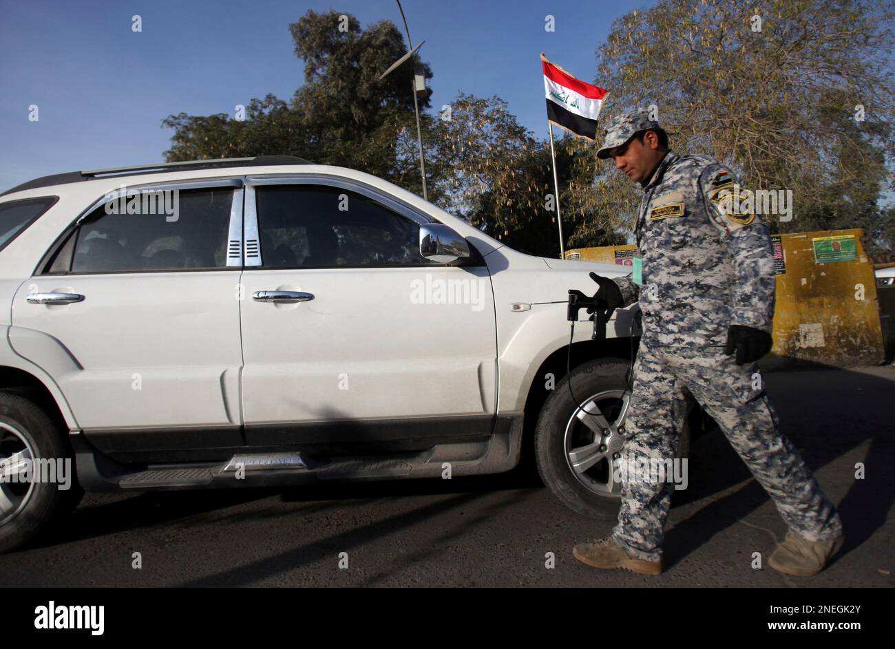 An Iraqi police officer uses a scanner device to inspect a car at ...