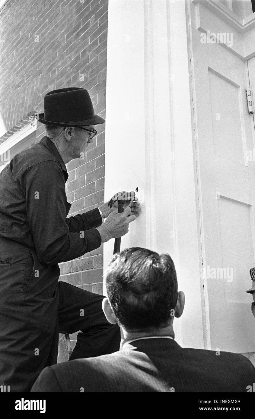 An unidentified workman probes for a bullet which smashed a large hole ...