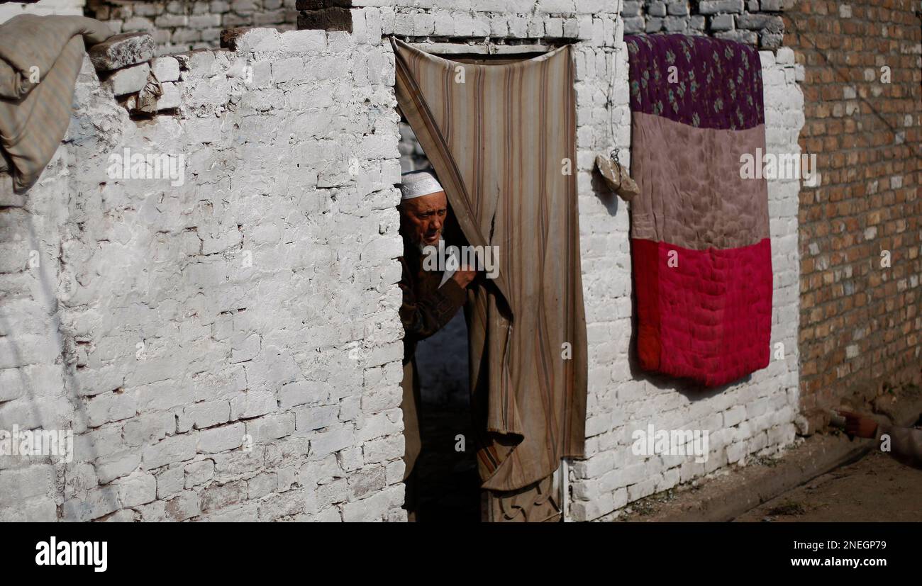 An elderly Pakistani man, talks to a child, from the entrance of his ...