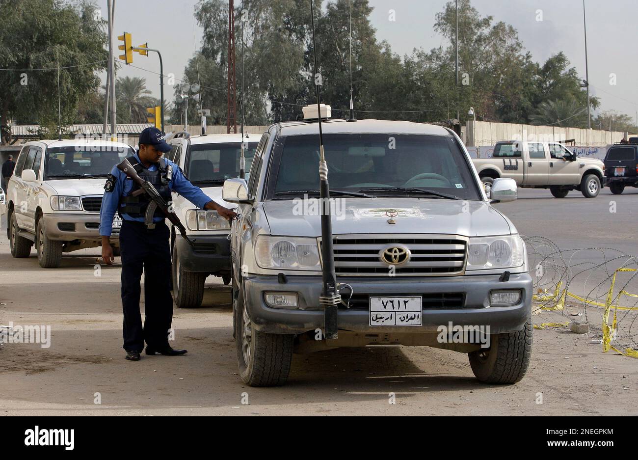 An Iraqi police officer stands guard near armored SUVs used by private ...